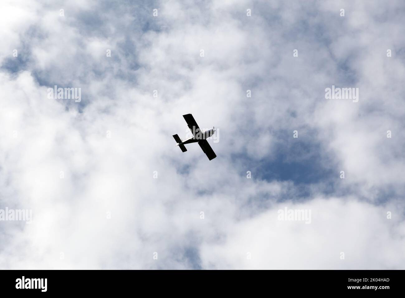 Light aircraft flies in cloudy sky on a daytime, silhouette photo Stock ...