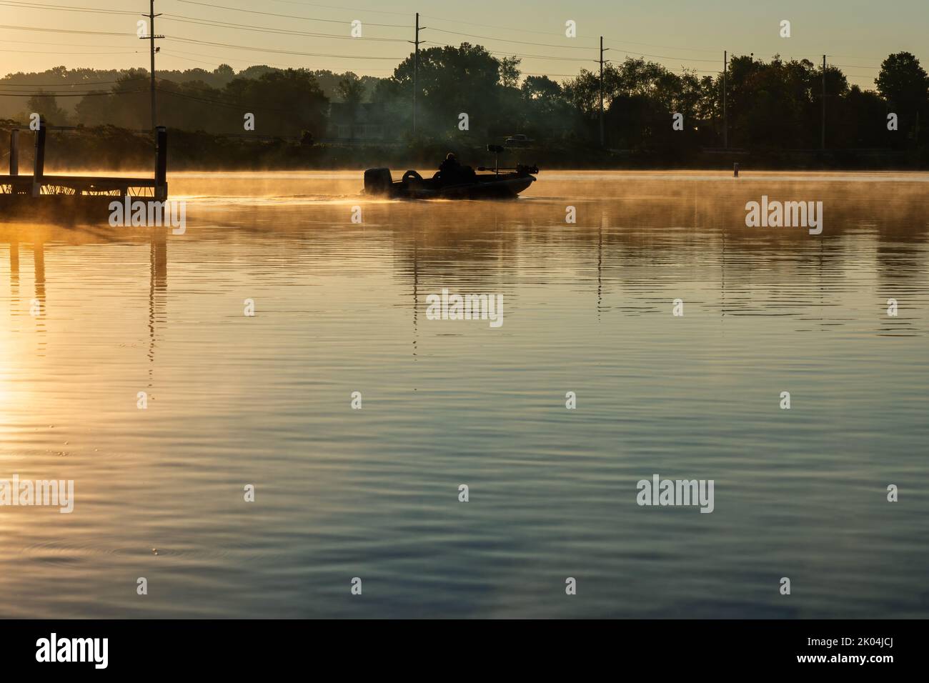 A man going bass fishing in a bass boat early morning sunrise on a ...