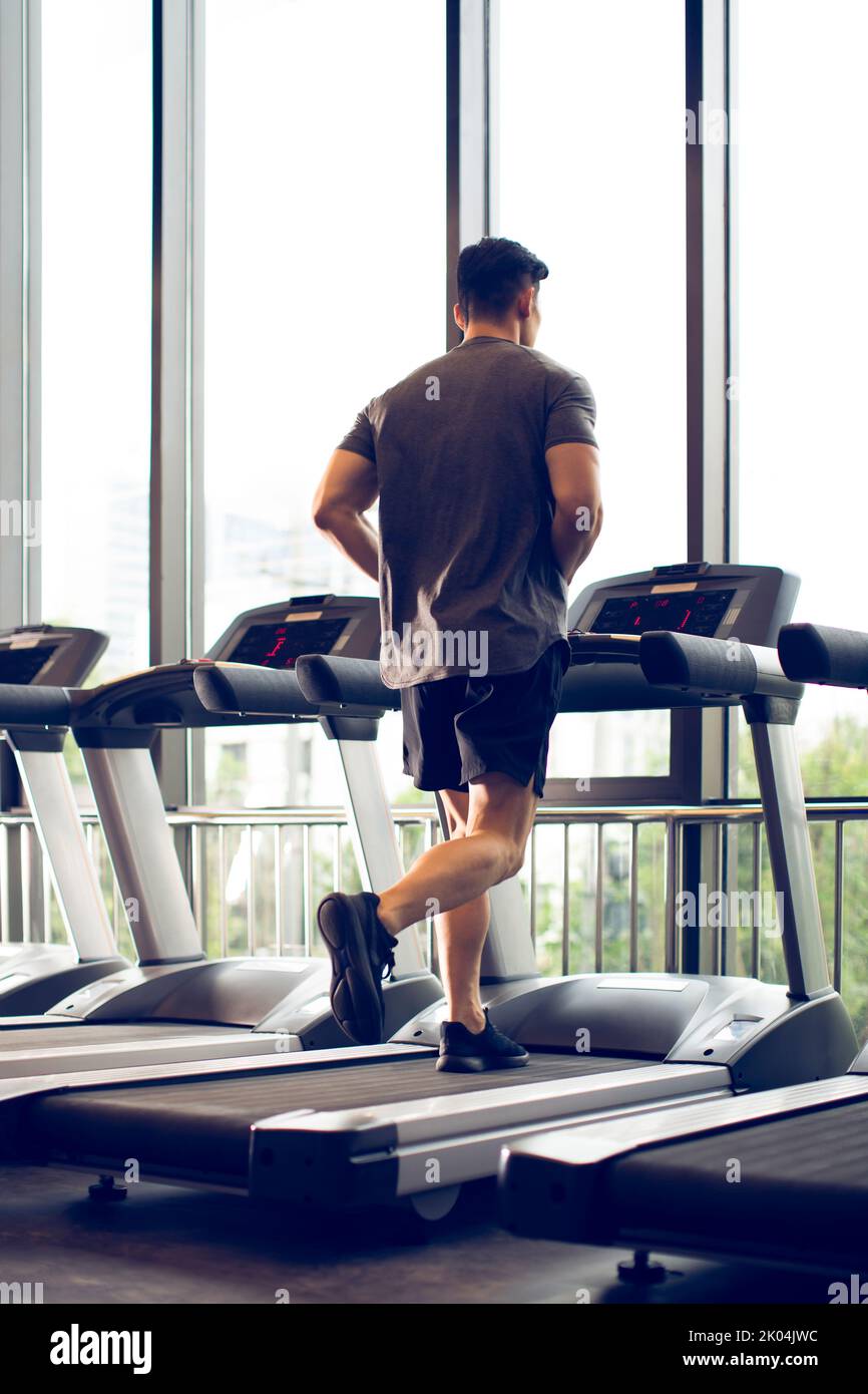 Young Chinese man running on treadmill at gym Stock Photo - Alamy