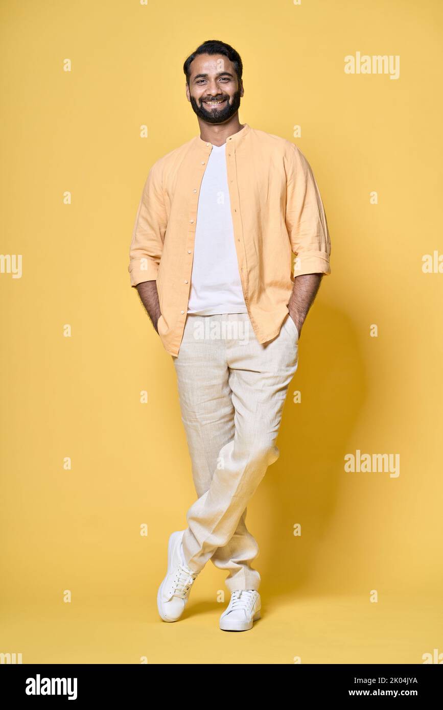 Smiling confident indian man standing isolated on yellow. Vertical full ...