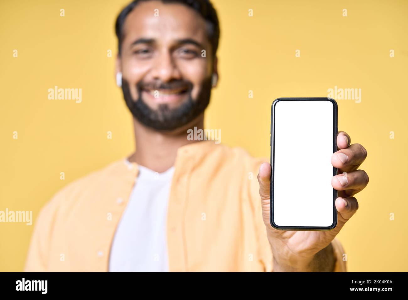 Happy indian man showing mobile phone mockup screen isolated on yellow Stock Photo - Alamy