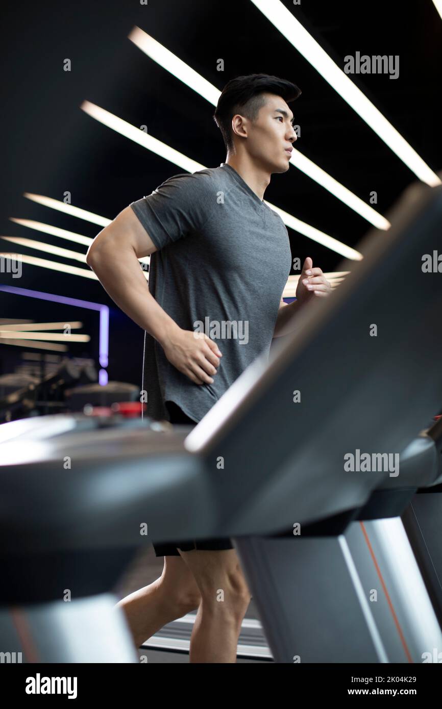 Young Chinese man running on treadmill at gym Stock Photo - Alamy