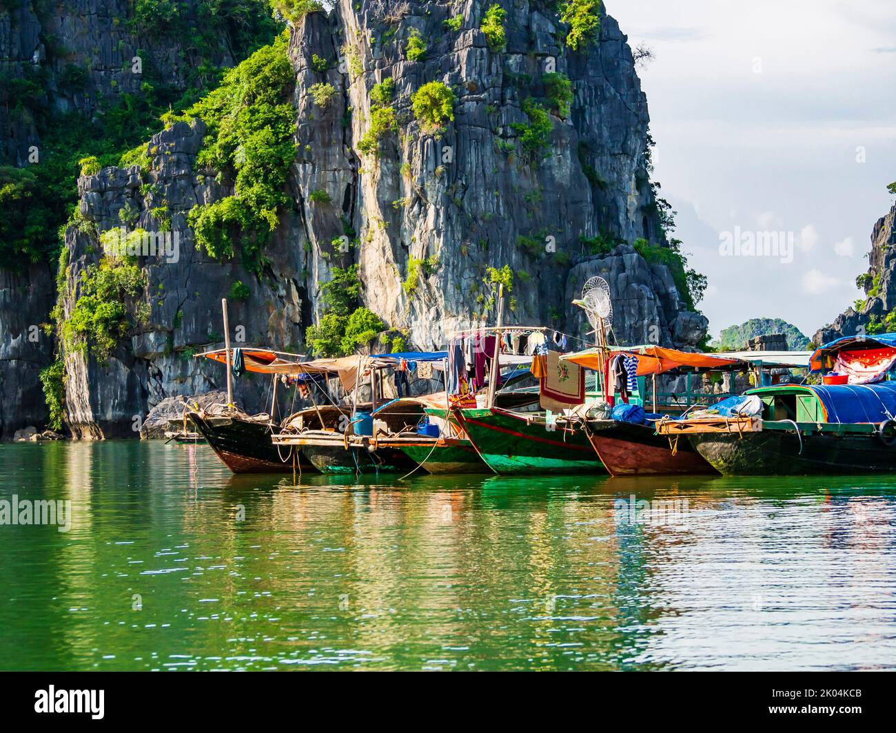 Multicolored fishing boats reflected in the emerald waters of Ha Long ...