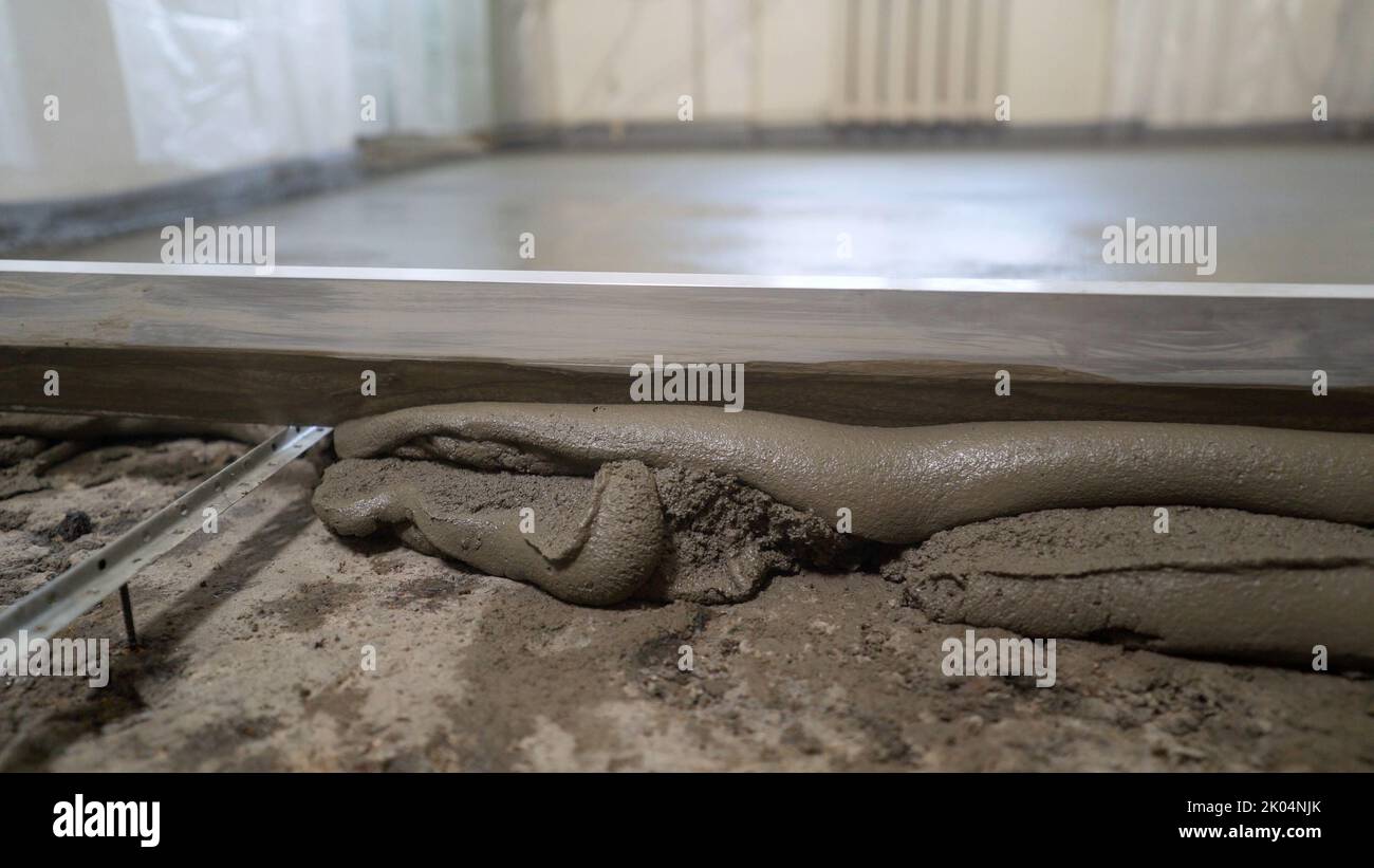 Leveling the mortar on the floor using metal guides. The master levels ...