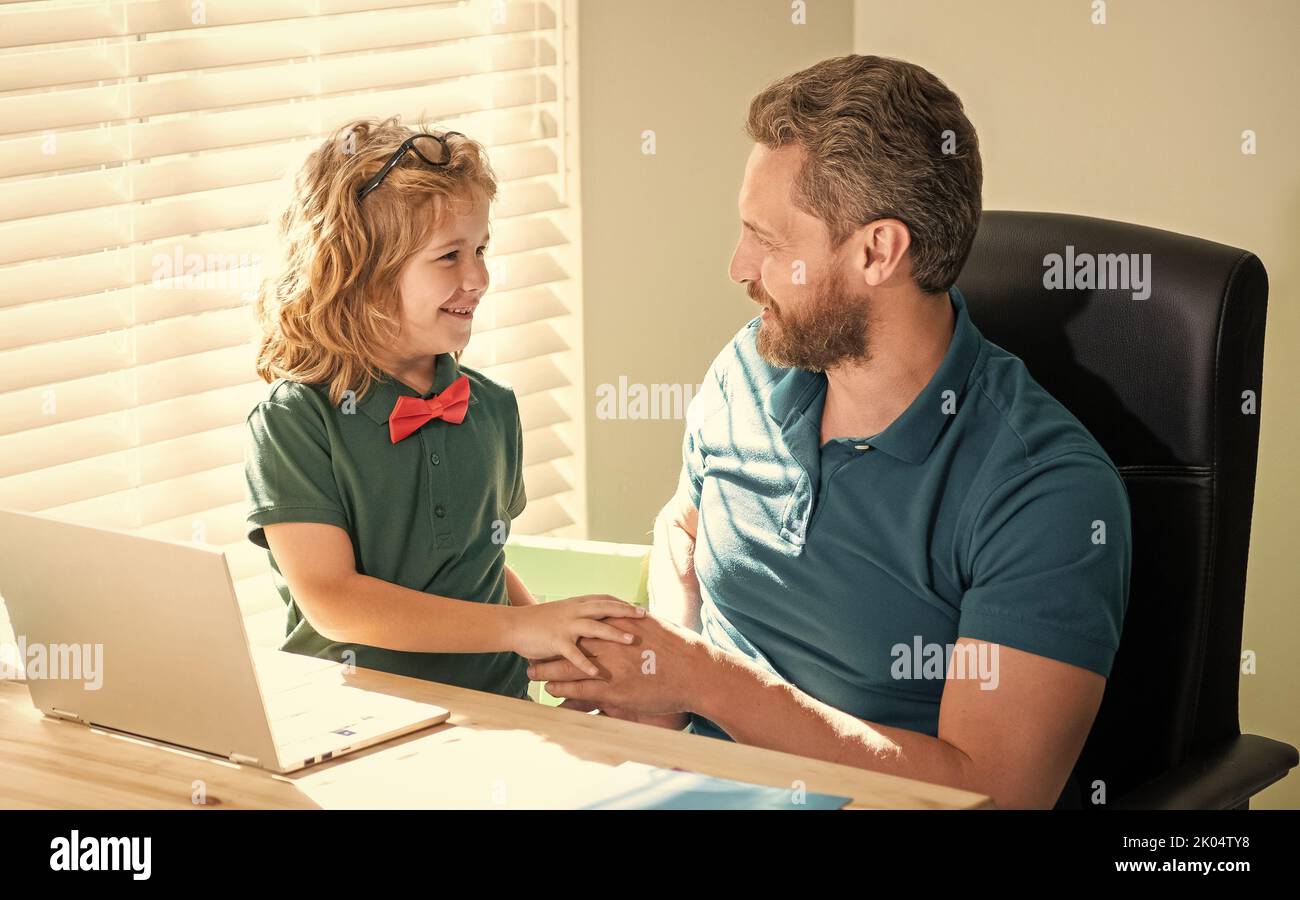 back to school. cheerful dad and son in glasses use laptop at home ...
