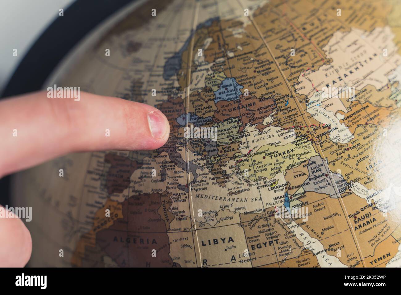 Close-up human finger pointing at a spot on a spinning geographical ...