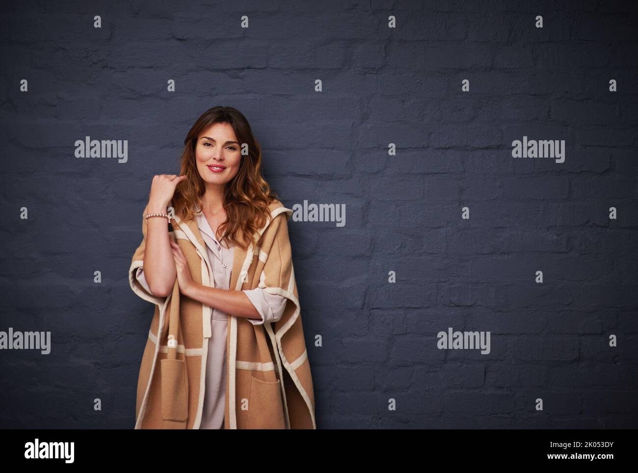 Stylish and cosy. a woman standing against a dark background Stock ...