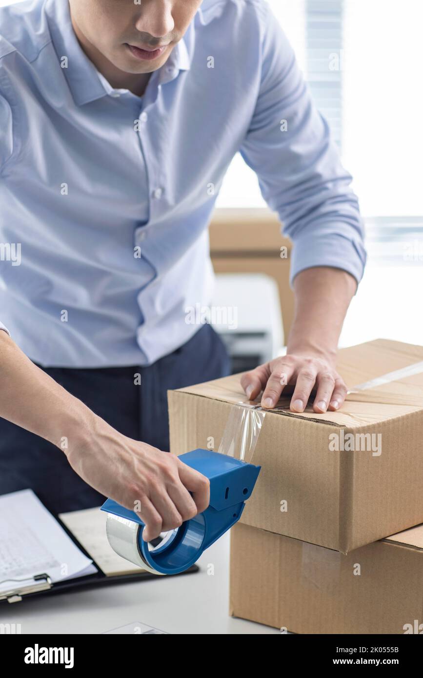 Chinese small business owner packing boxes in office Stock Photo - Alamy