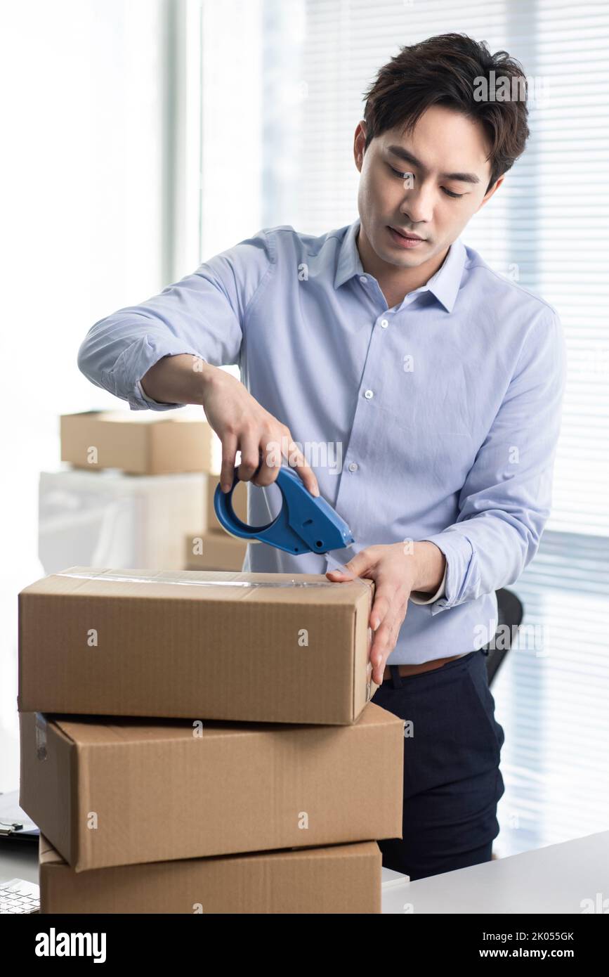 Chinese small business owner packing boxes in office Stock Photo - Alamy