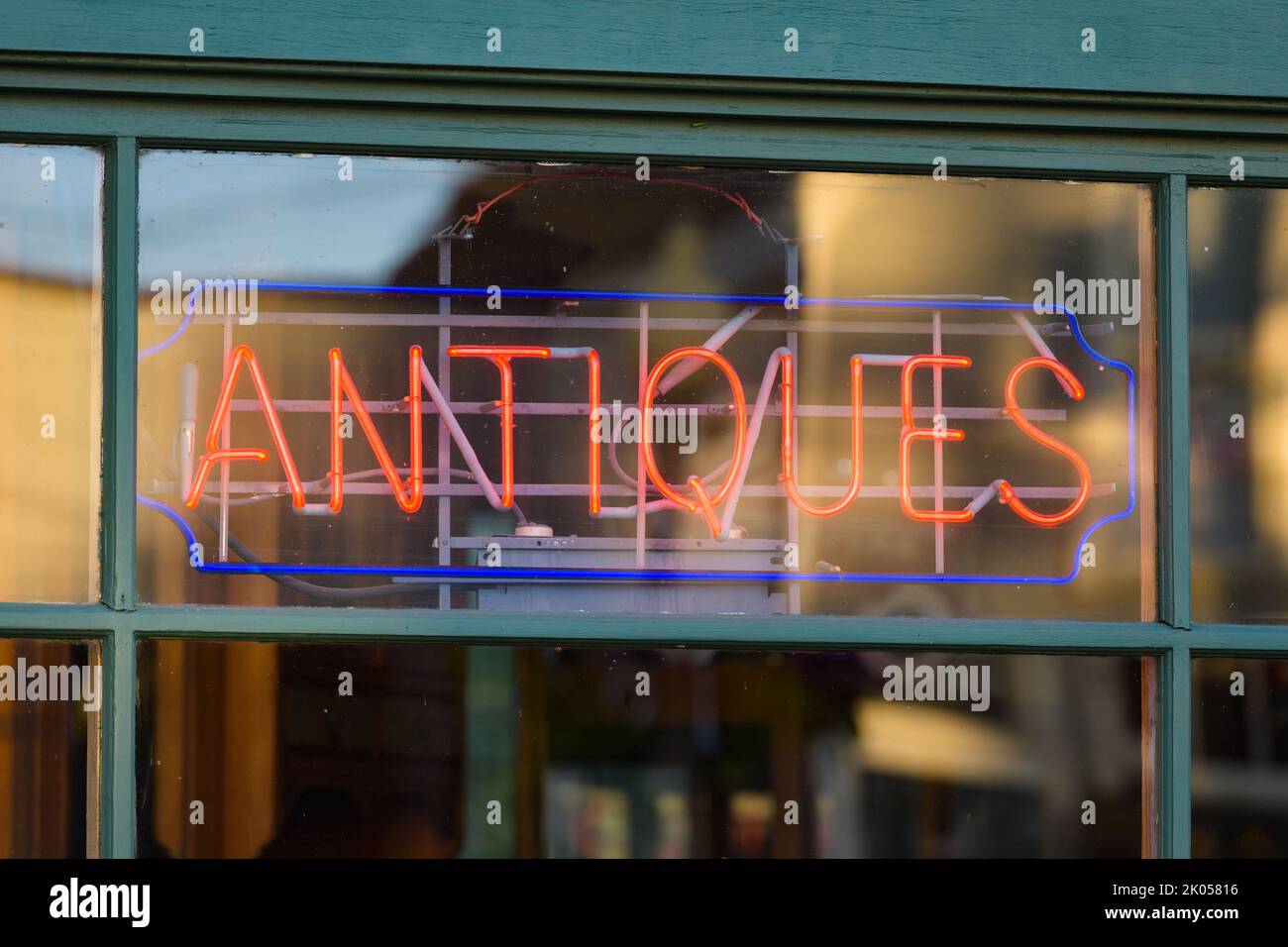 Shop window neon sign spelling antiques in red with green wood window ...