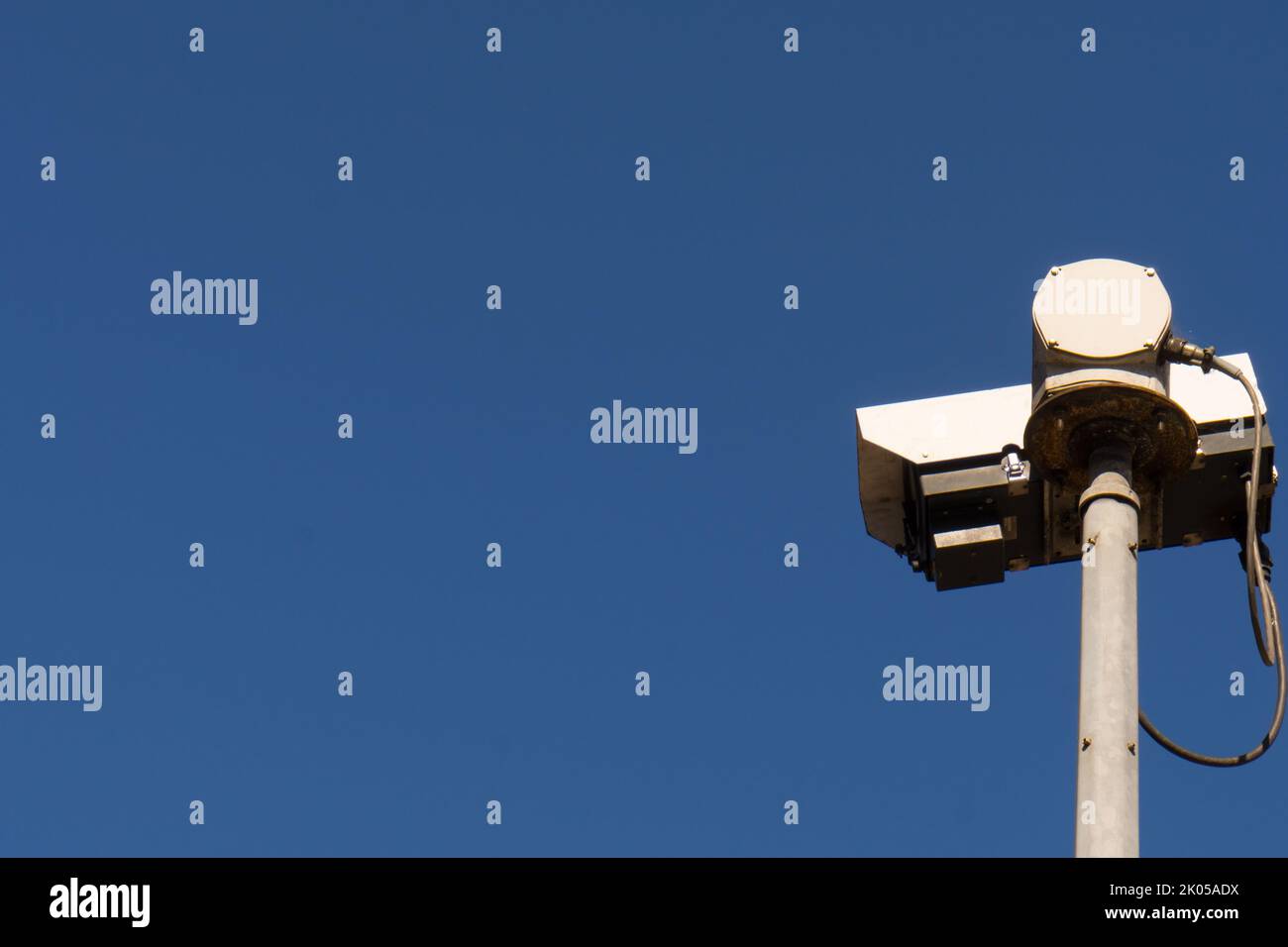 Close up of a pole with mounted surveillance video camera against blue ...