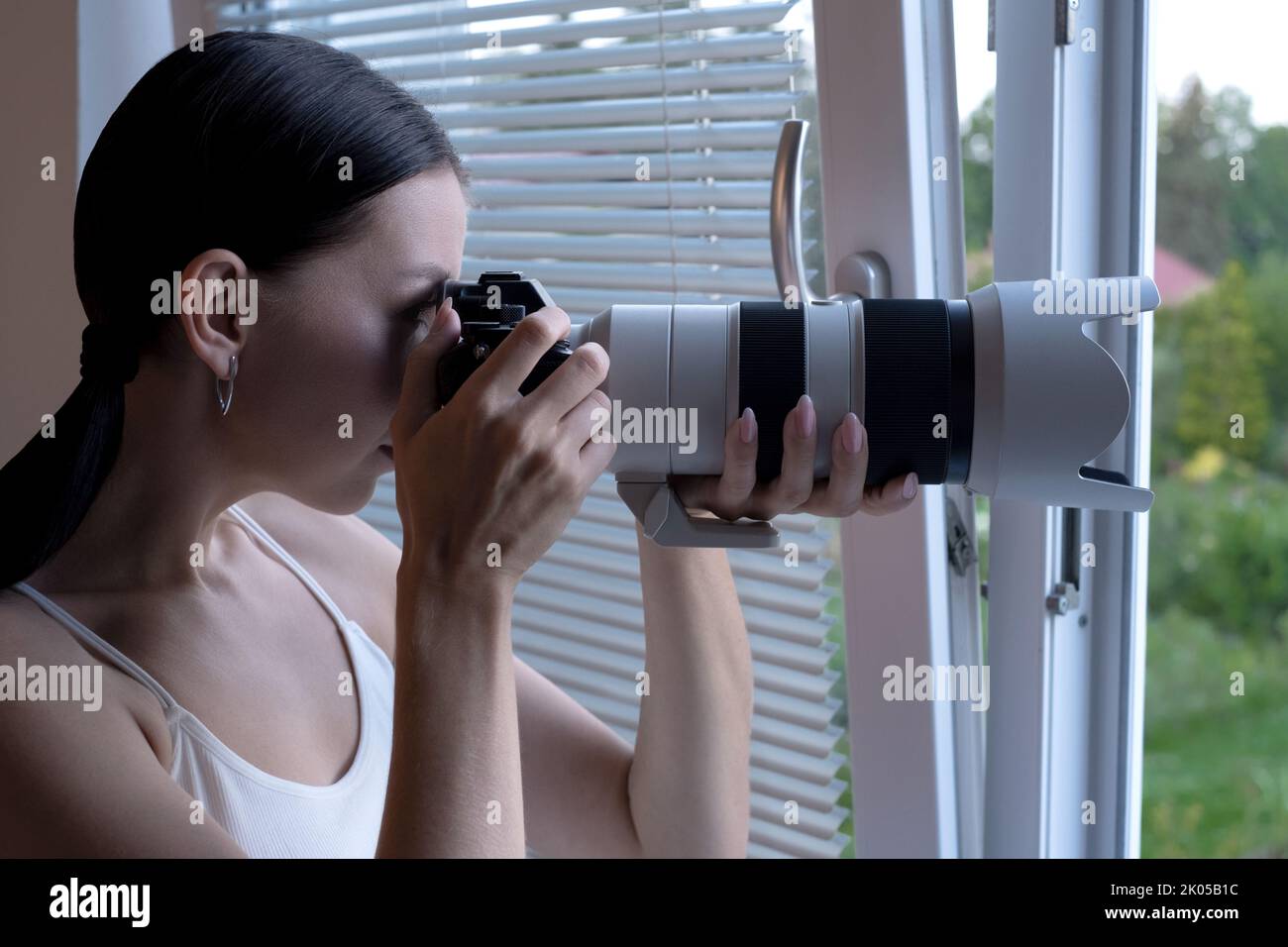 Young woman Paparazzi Photographer Capturing A Photo from an apartment ...