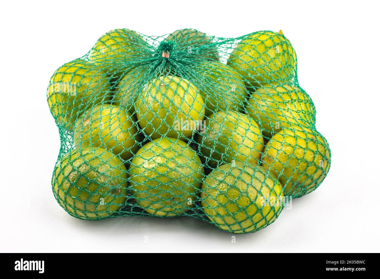 Fresh limes in the net green lime citrus fruit stand isolated on white background. Lime wedge ...