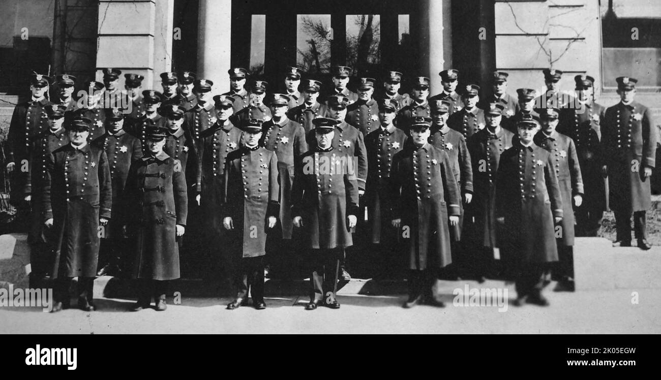 A squad of police officers pose on the front of the station house at an ...