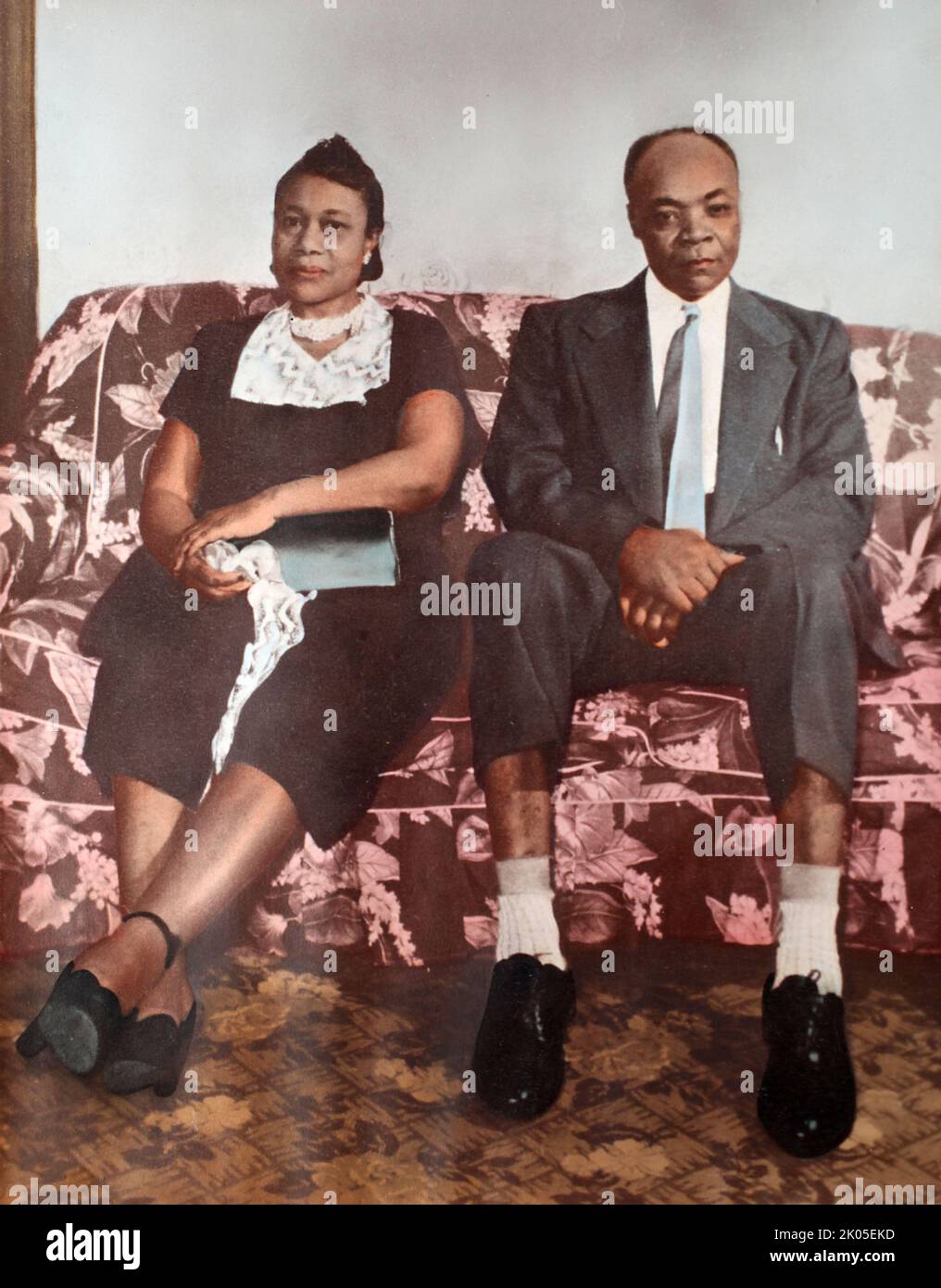 A middle class African American couple sit on their couch in their home ...