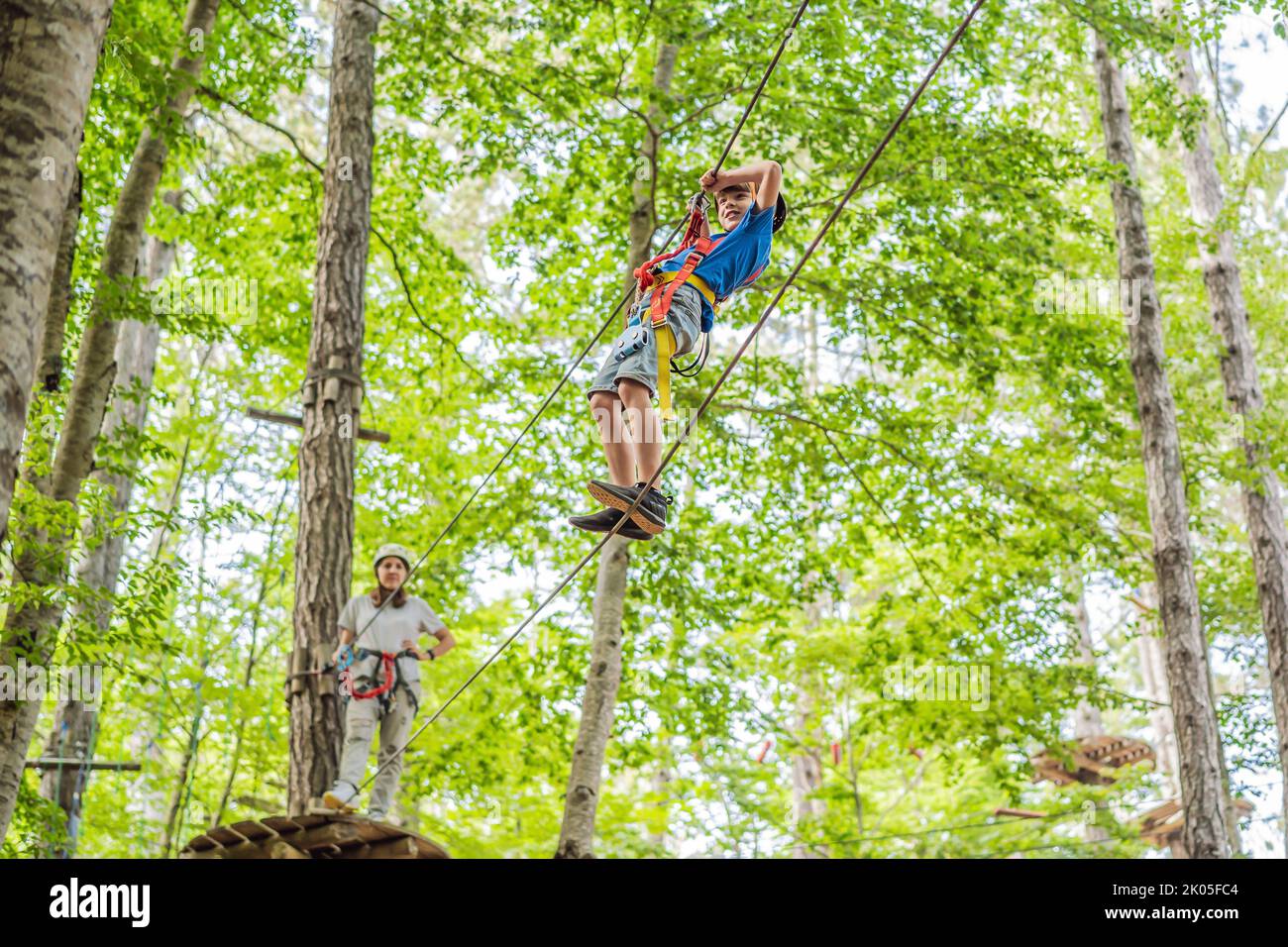 Mother and son climbing in extreme road trolley zipline in forest on ...