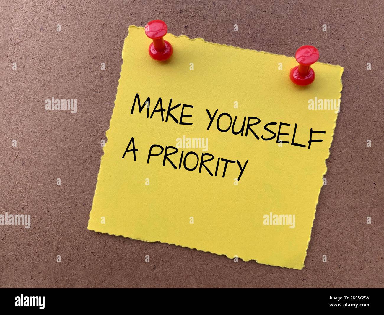 Make yourself a priority text on yellow notepad with wooden background ...