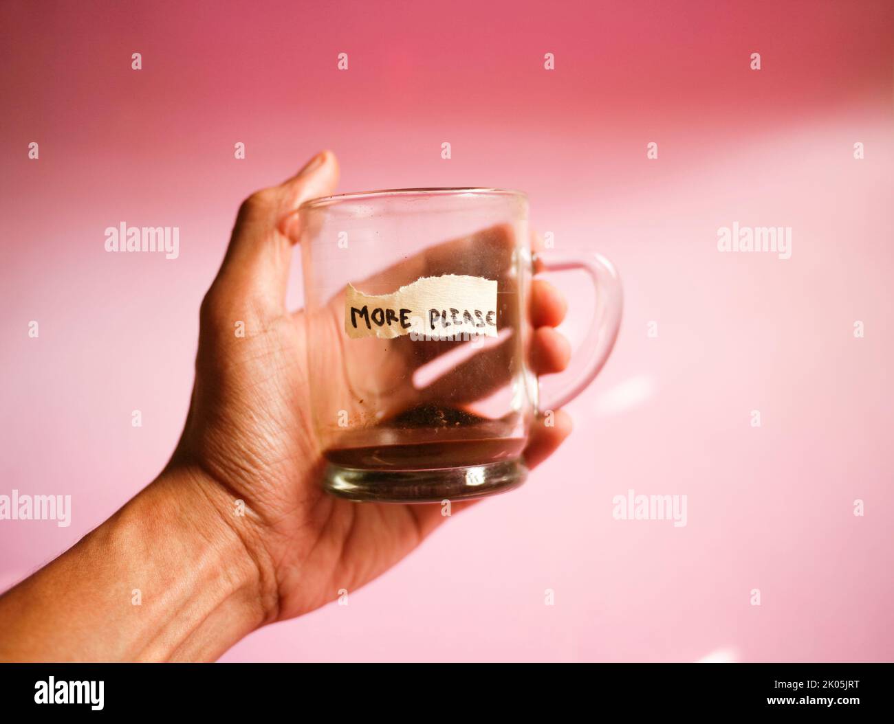 hand holding empty drinking glass of coffee with text word more please ...