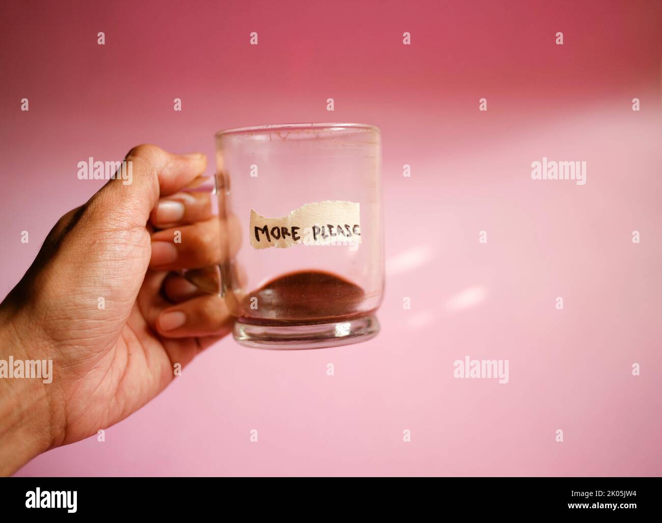 hand holding empty drinking glass of coffee with text word more please ...