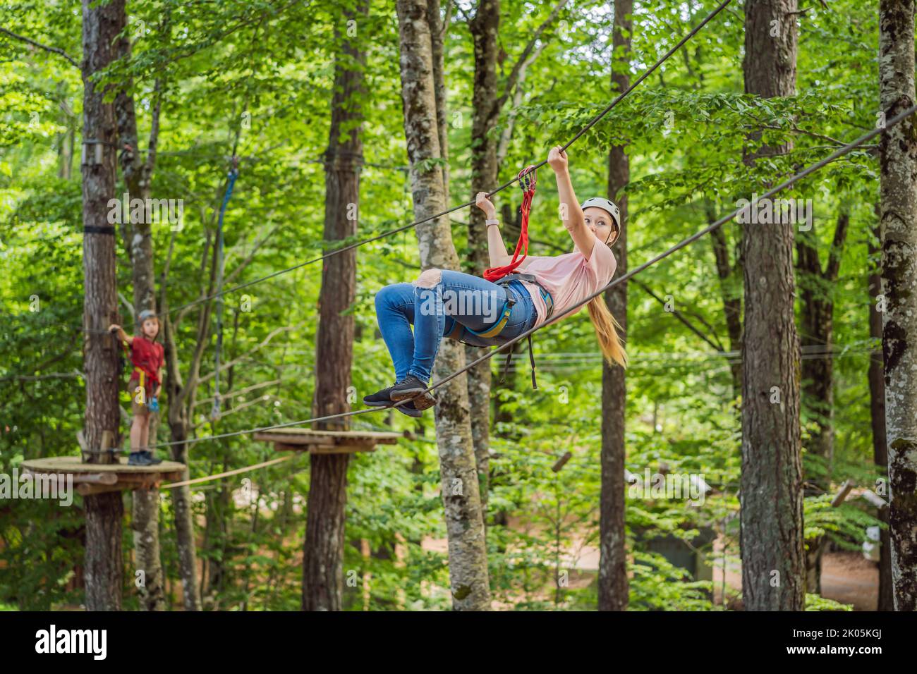 Mother and son climbing in extreme road trolley zipline in forest on ...