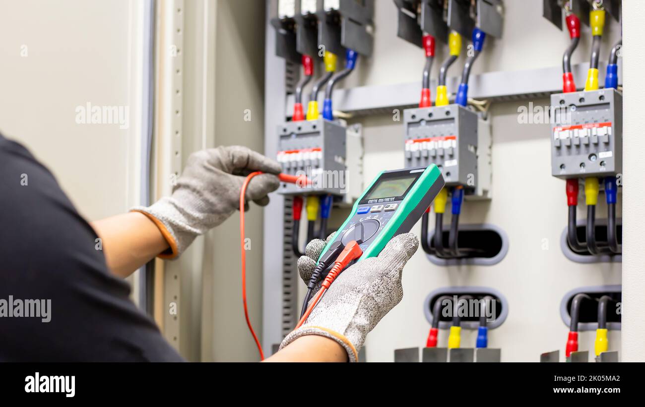 Engineers working to inspect and maintain electrical control cabinets ...