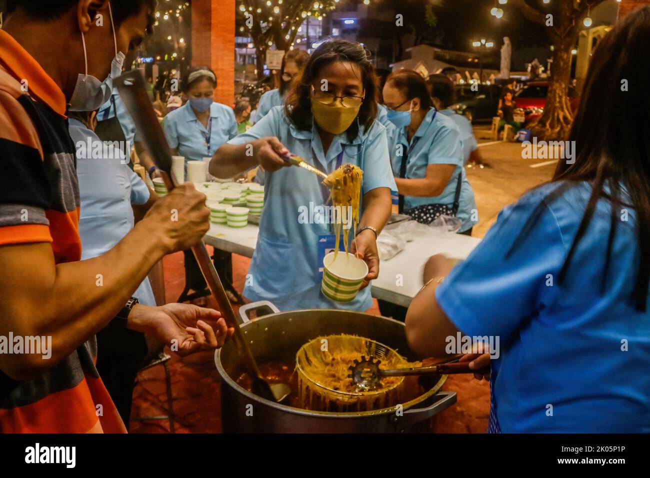 Volunteers from the catholic church distributing noodle soup in meal ...