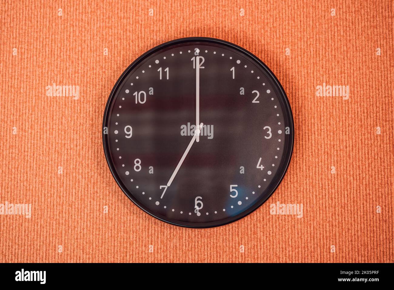 Classic black and white analog clock on red background at One o'clock ...