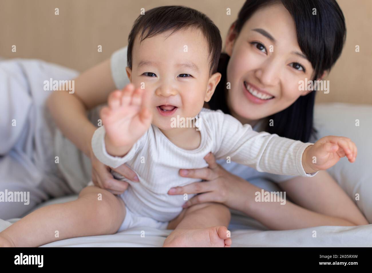 Cheerful young Chinese mother playing with baby Stock Photo - Alamy