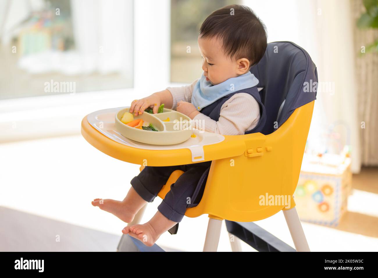 Cute Chinese baby sitting in high chair Stock Photo - Alamy