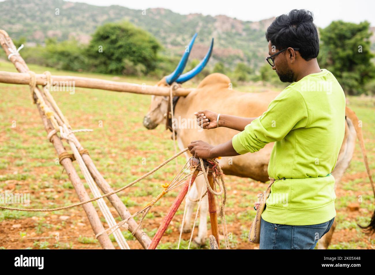 modern Indian young man trying ploughing or traditional farming at ...