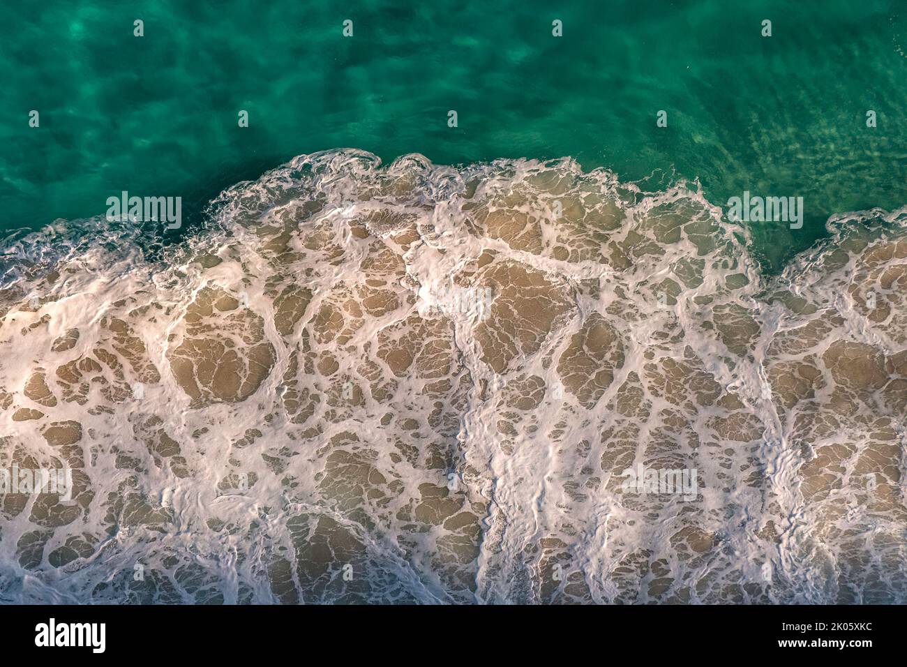 Top view of patterns of white foam from the impact of ocean waves on ...