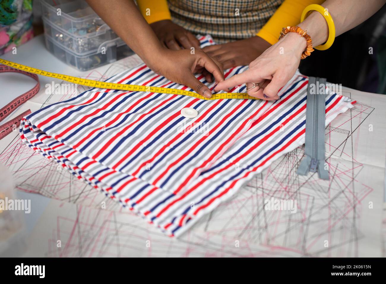 With his finger, he points to a button that lies on the fabric. Tailor ...