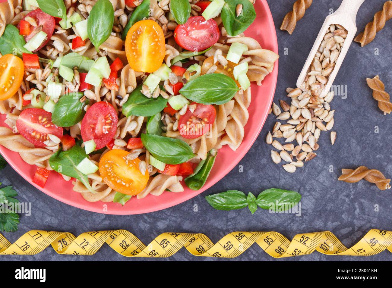 Tape measure and fresh prepared salad with wholegrain pasta and ...