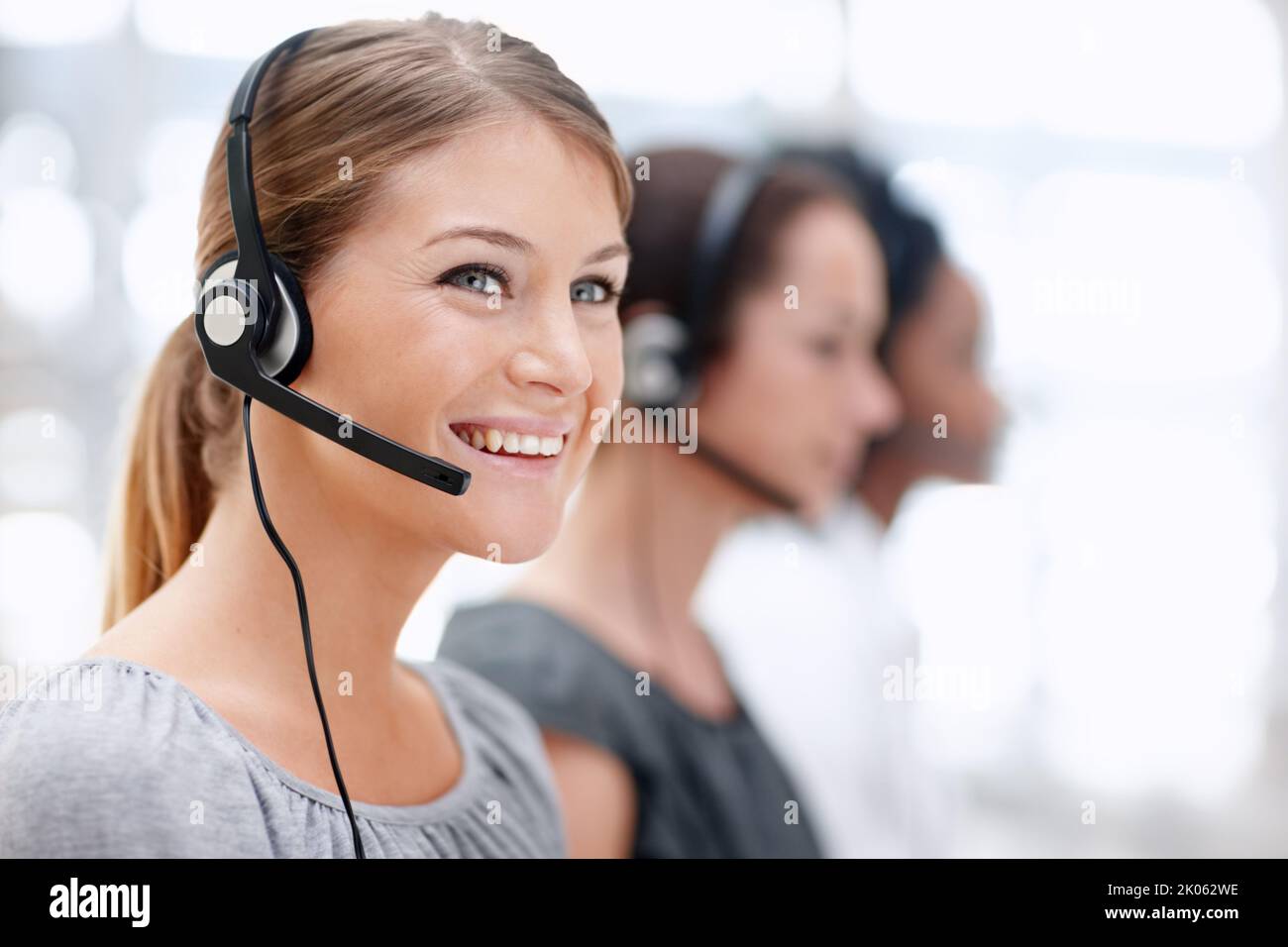 Every customer is satisfied. Pretty young call operator smiling as she ...