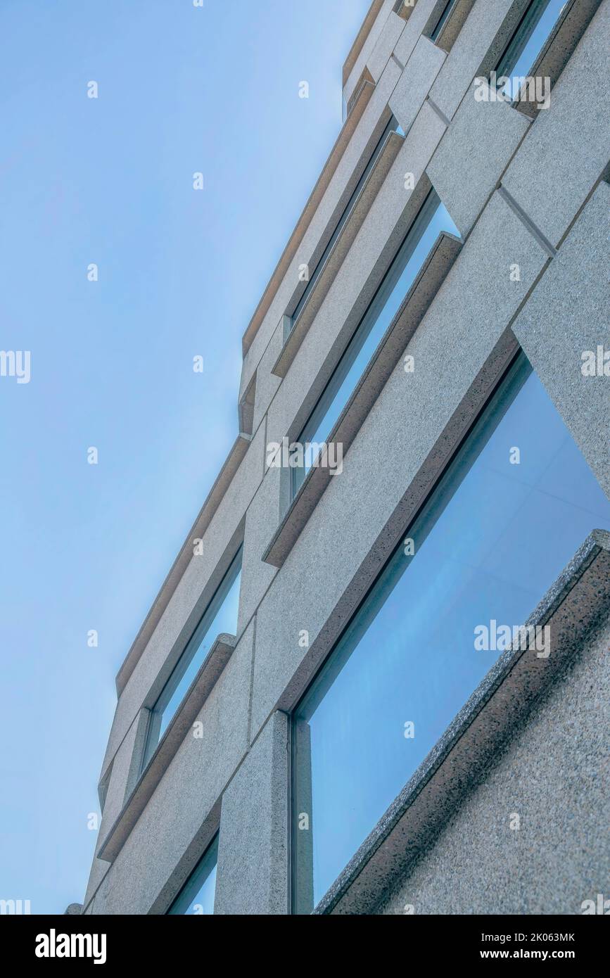 Modern building with windows that reflects blue sky viewed from below ...