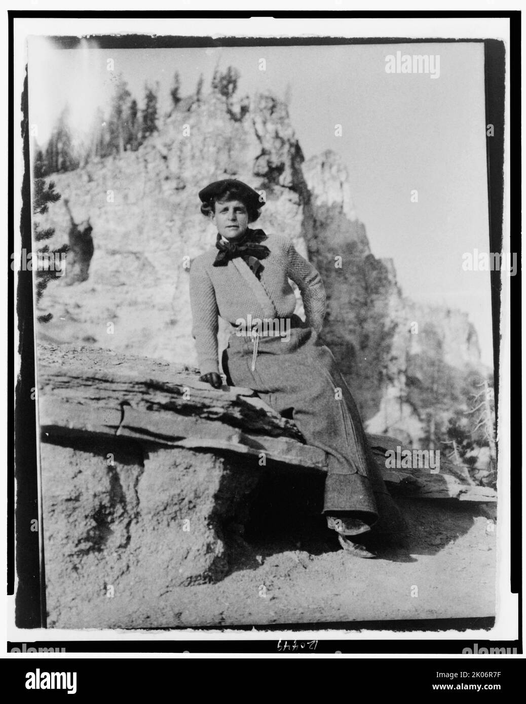 Frances Benjamin Johnston, full-length portrait, seated on rock in ...