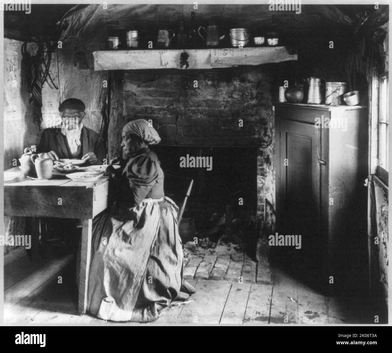 Old African American couple eating at the table by fireplace, rural ...