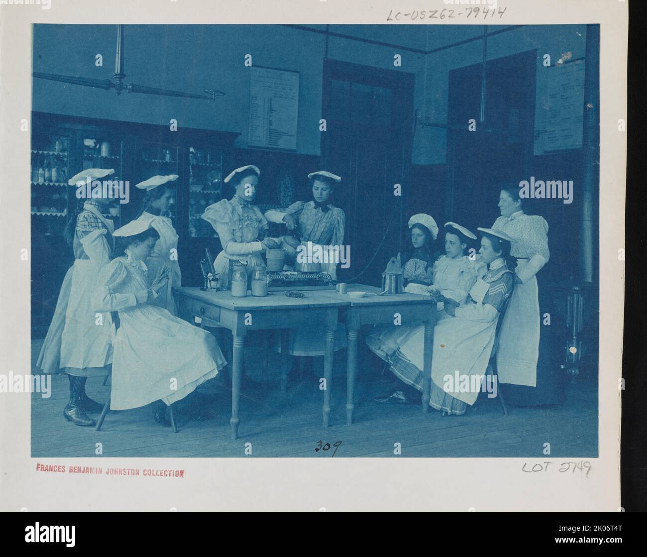 Eight teenage girls wearing aprons and chef caps learning to cook as ...