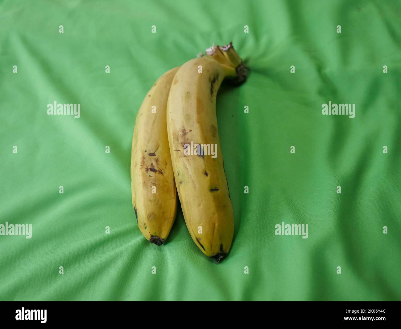 Two yellow ripe Banana placed in green background Stock Photo - Alamy