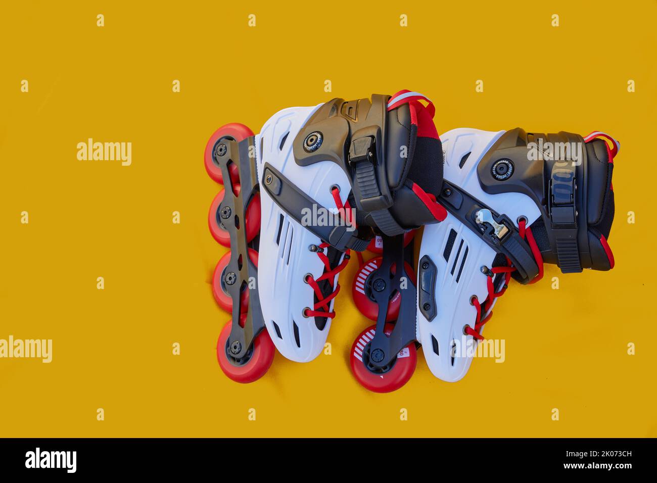 Pair of inline skates one on top of the other on yellow background with ...