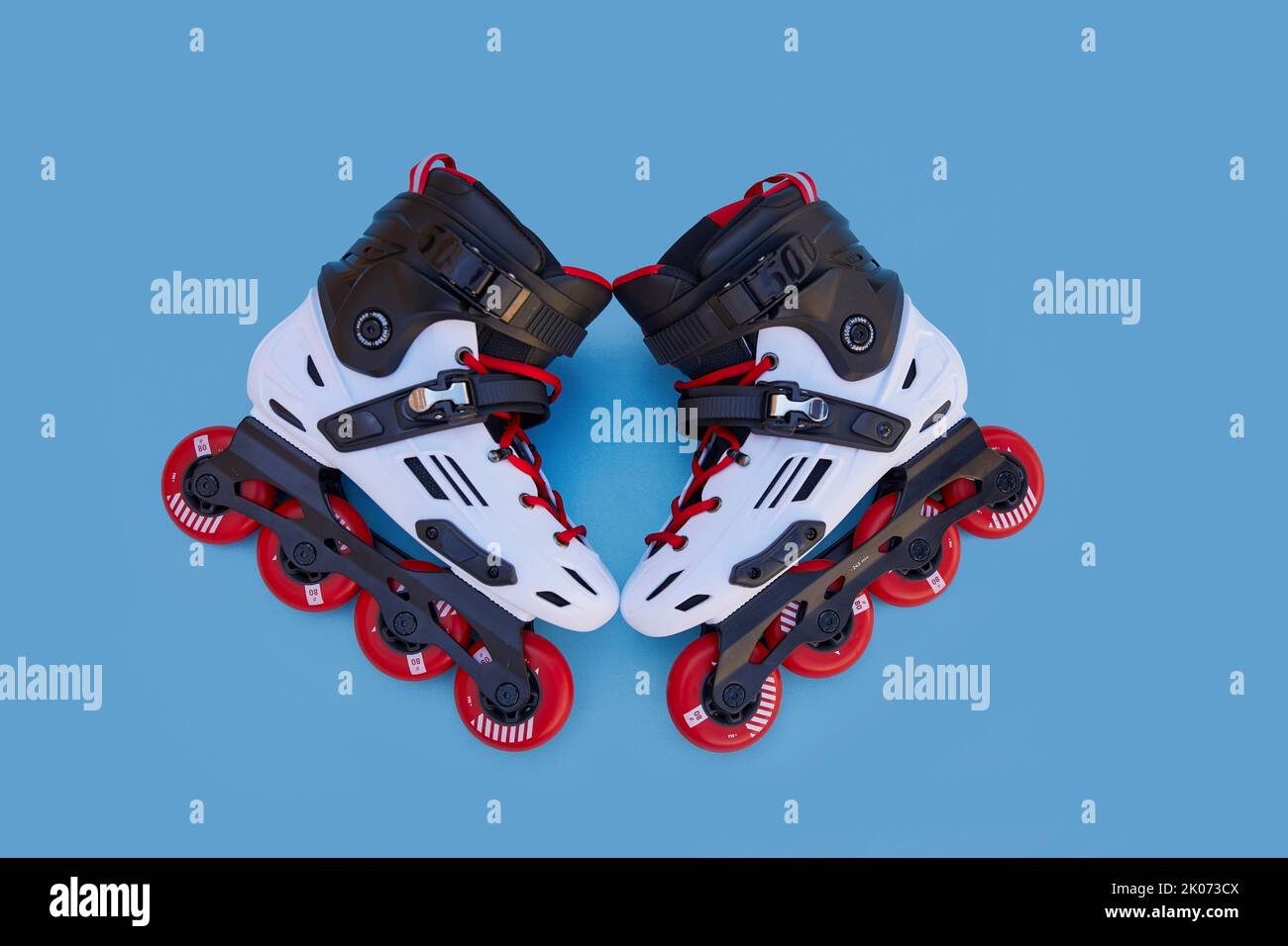 Pair of white inline skates facing each other on blue background with ...