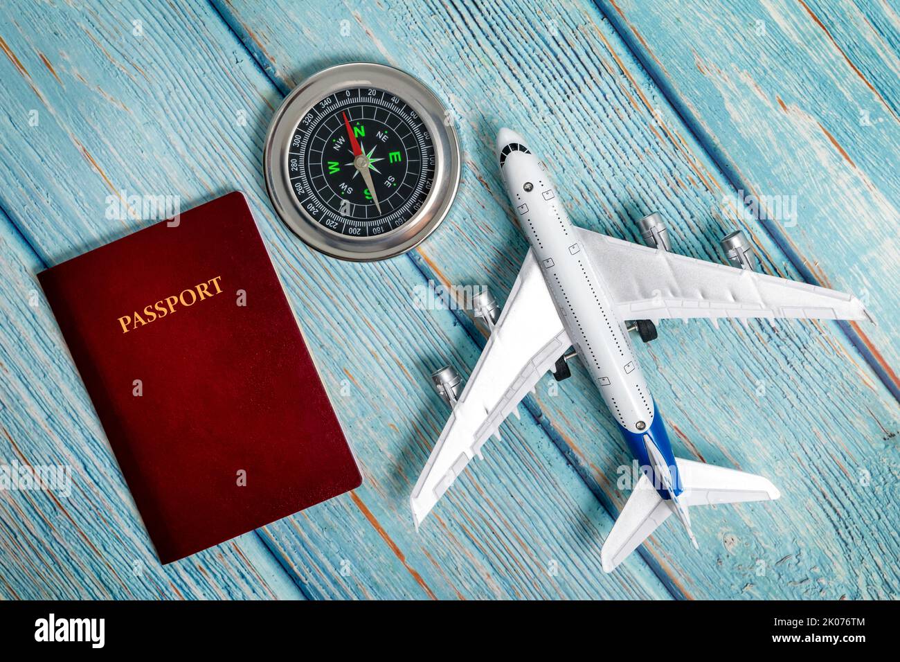 Passenger airplane model with passport and compass, on blue wooden ...