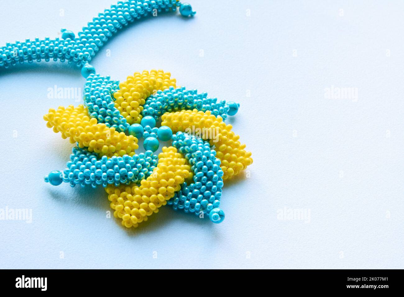 Square plait of yellow-blue beads, on a white background, space for ...