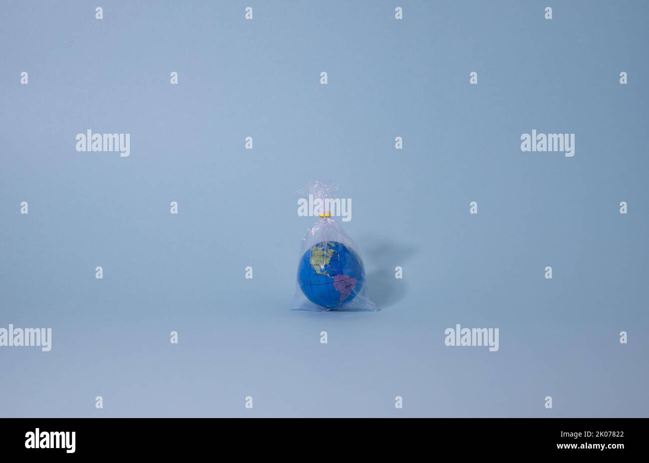 small earth inside plastic bag, pollution concept. blue background ...