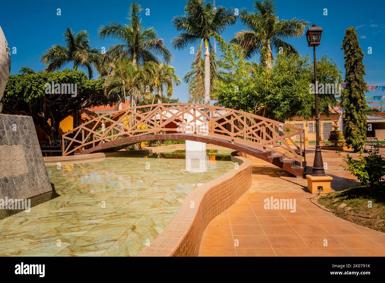 Side view of a small wooden bridge over a water fountain in a calm park ...