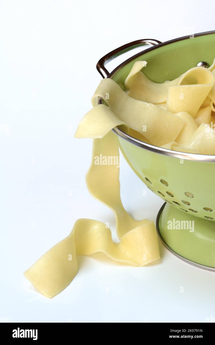 Pappardelle, cooked, wide Italian ribbon noodles in kitchen sieve ...
