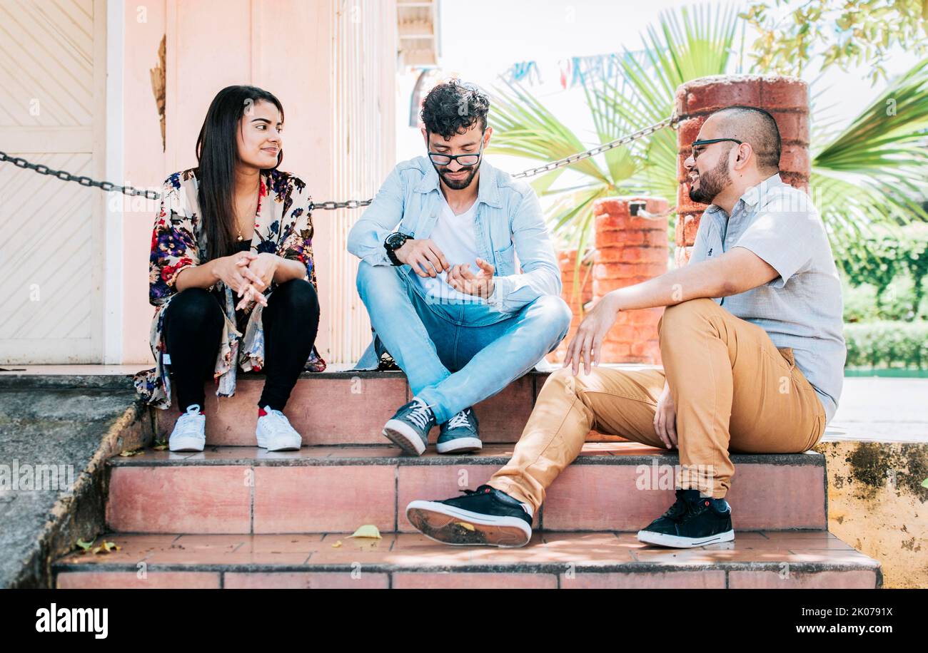Three teenage friends talking sitting on the stairs, Three young people ...
