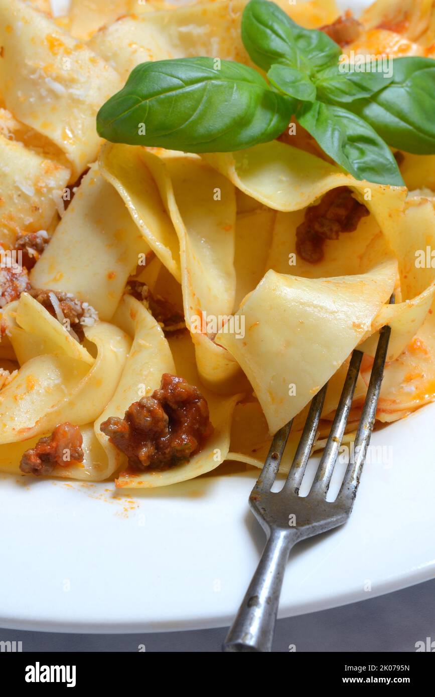 Pappardelle, cooked, wide Italian ribbon noodles with Bolognese sauce ...