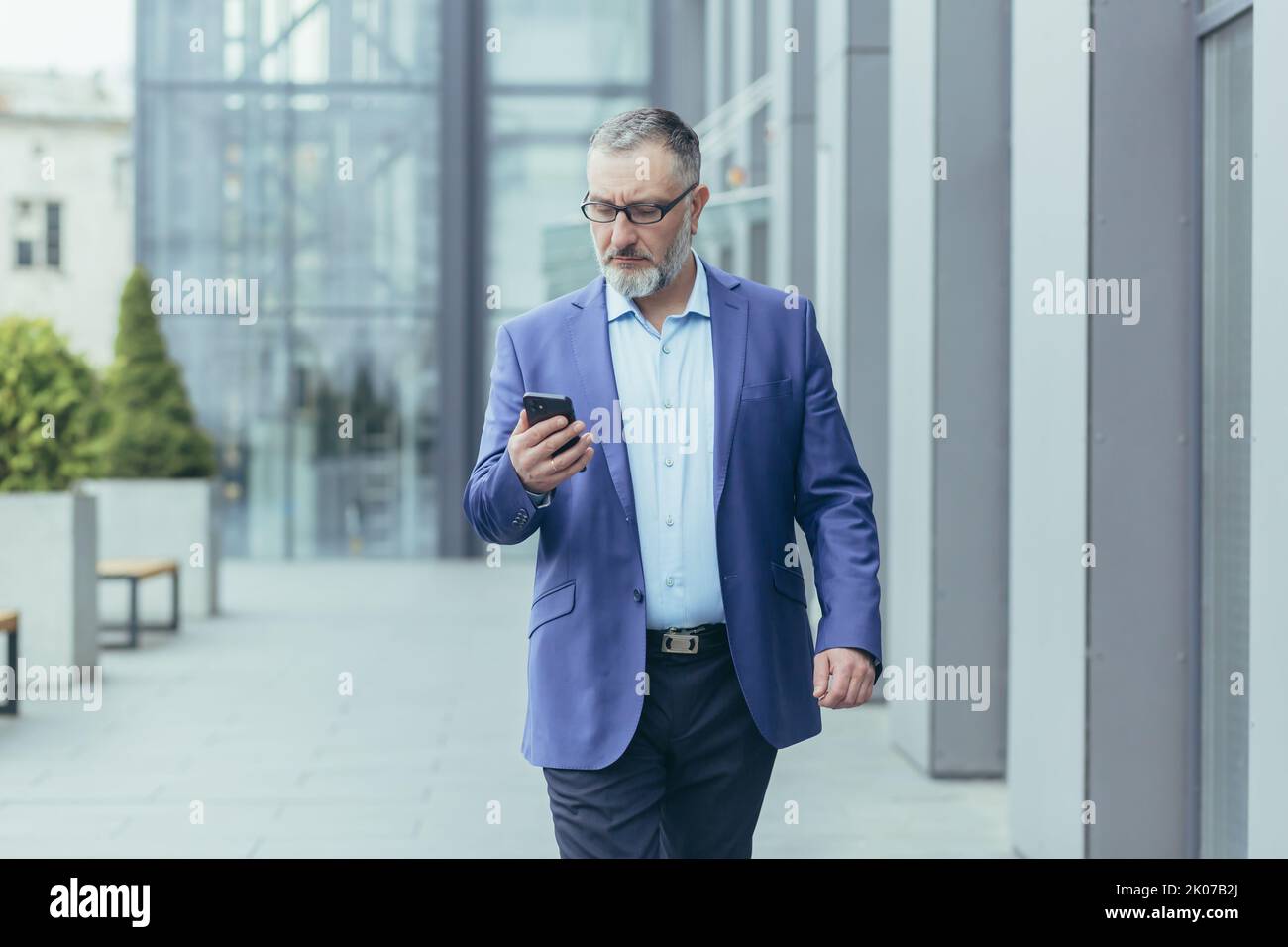 Serious gray-haired senior handsome man businessman in suit and glasses ...