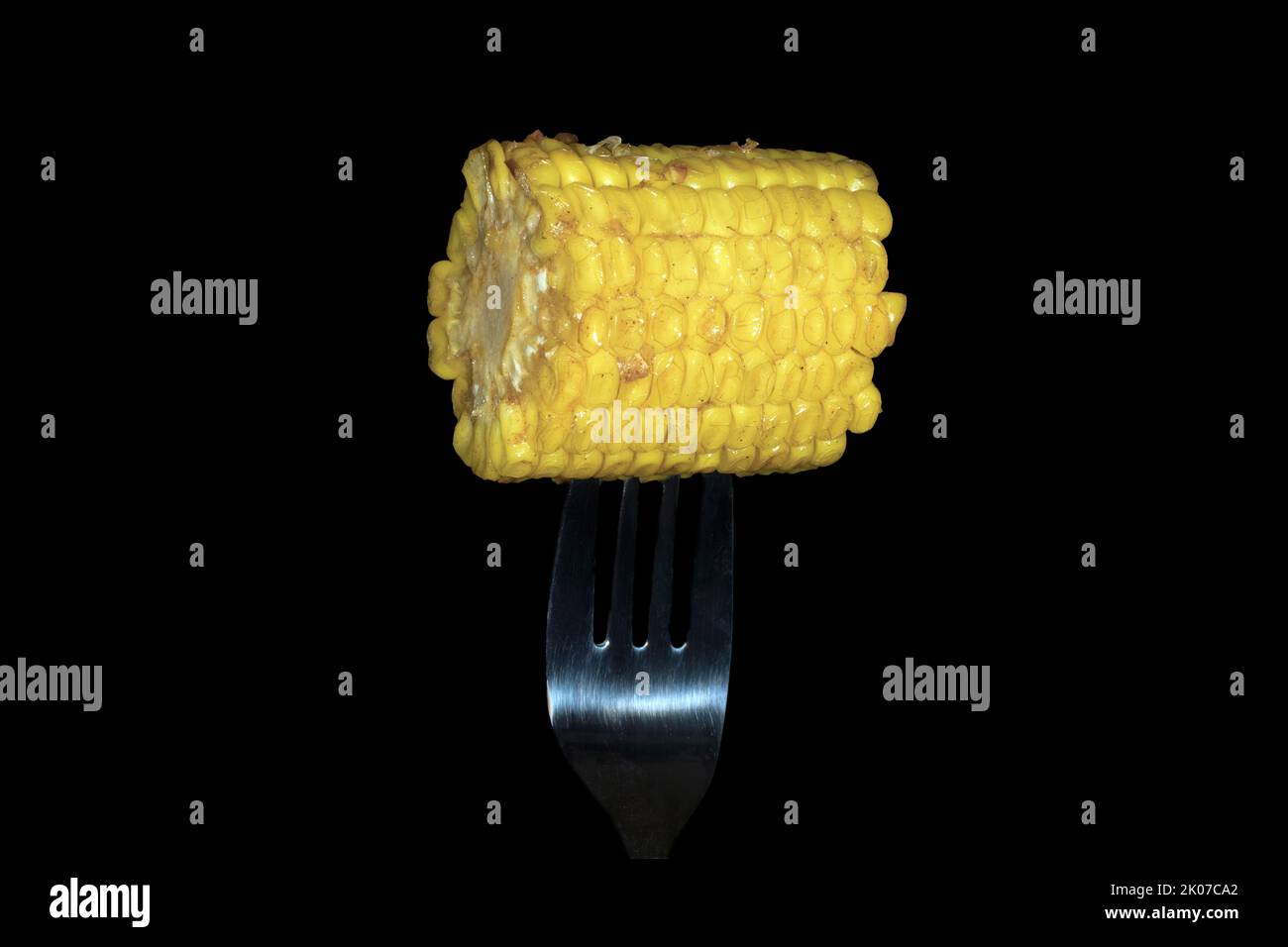 Butter fried hominy, corn (Zea mays) on the corn cob, stuck on a fork ...